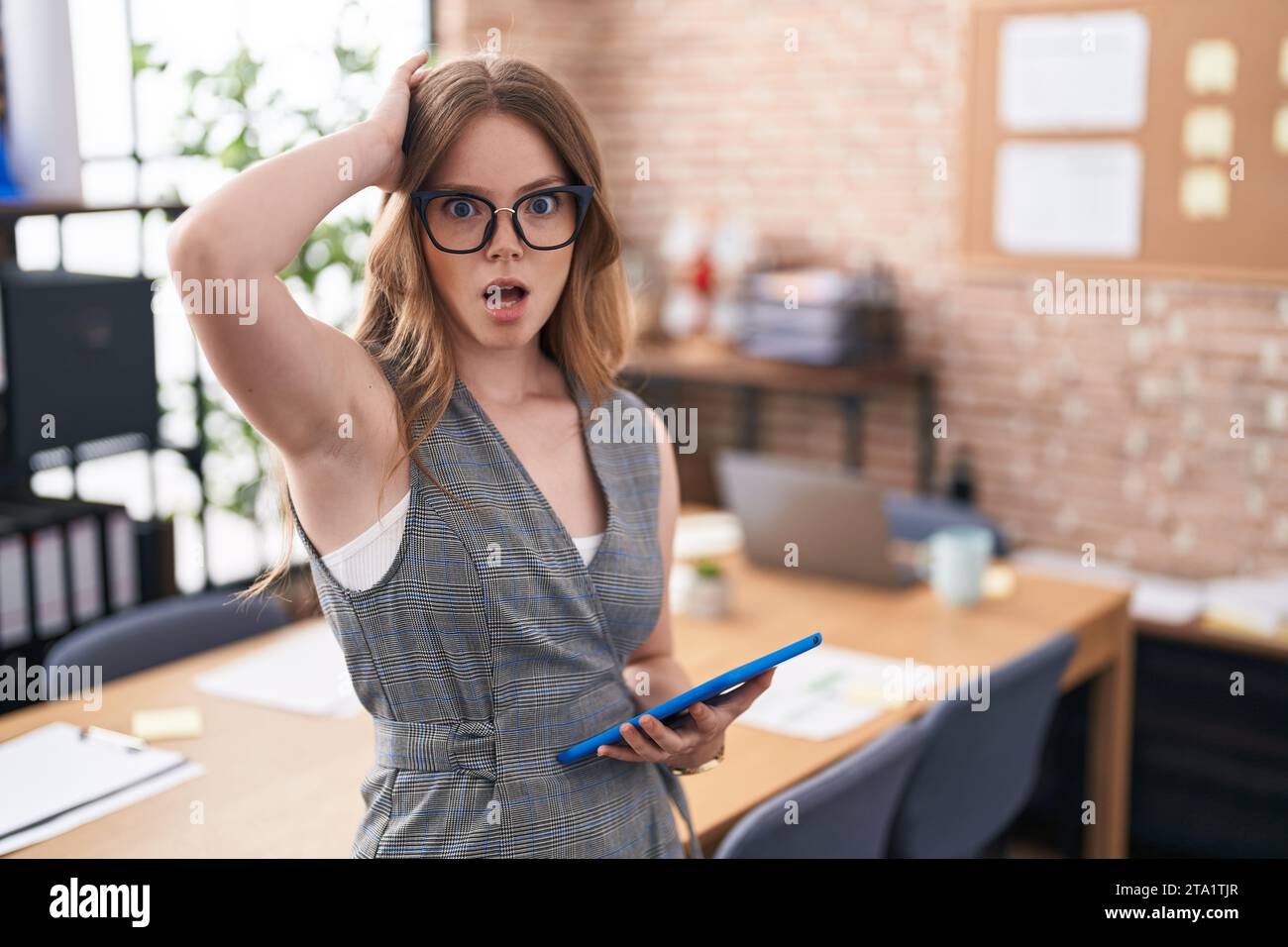 Caucasian woman working at the office wearing glasses crazy and scared ...