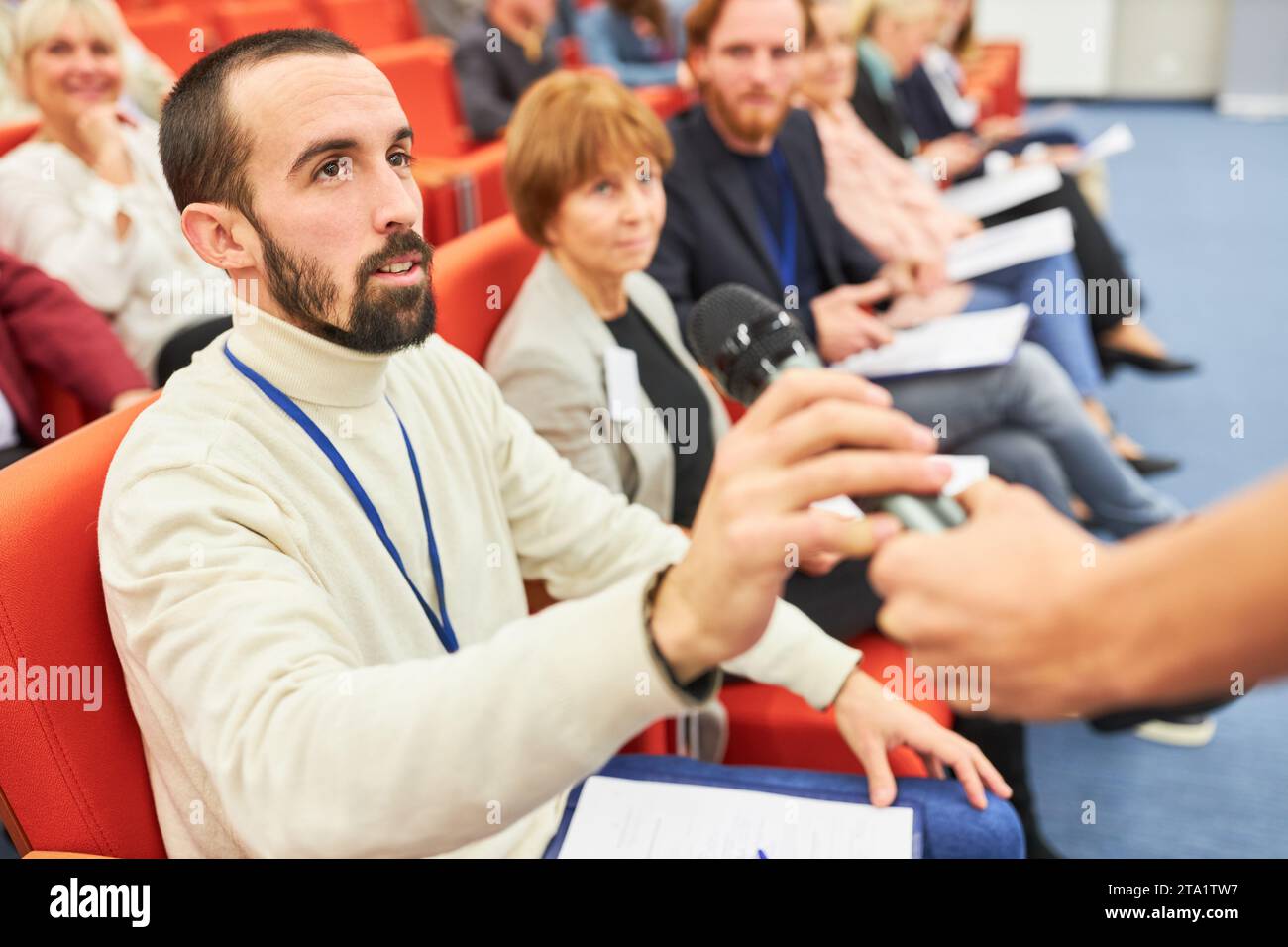 People in audience asking question with microphone at business ...