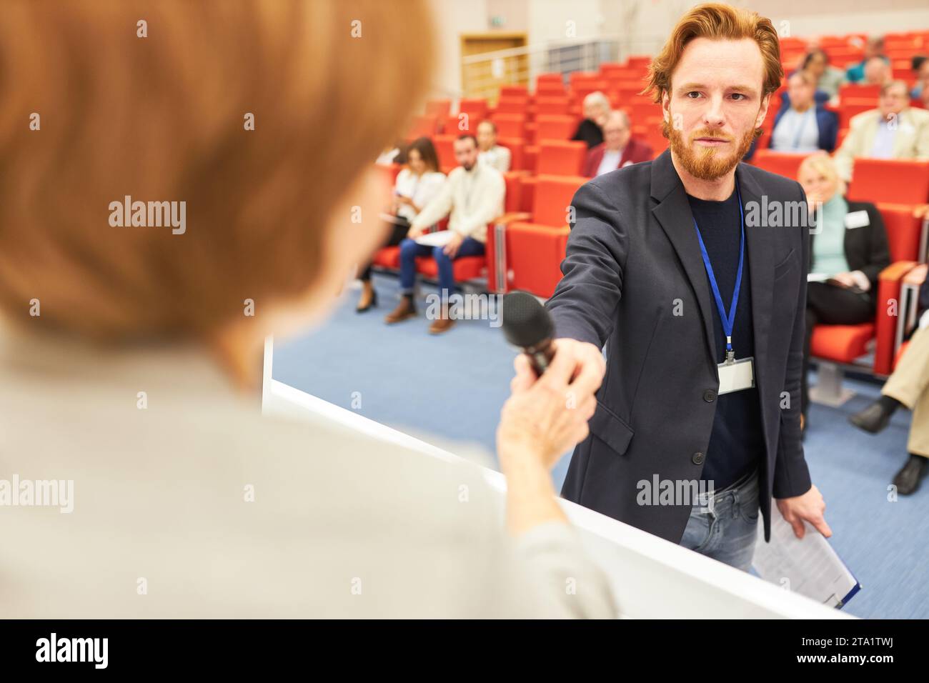 Speaker giving microphone to audience during interactive business ...