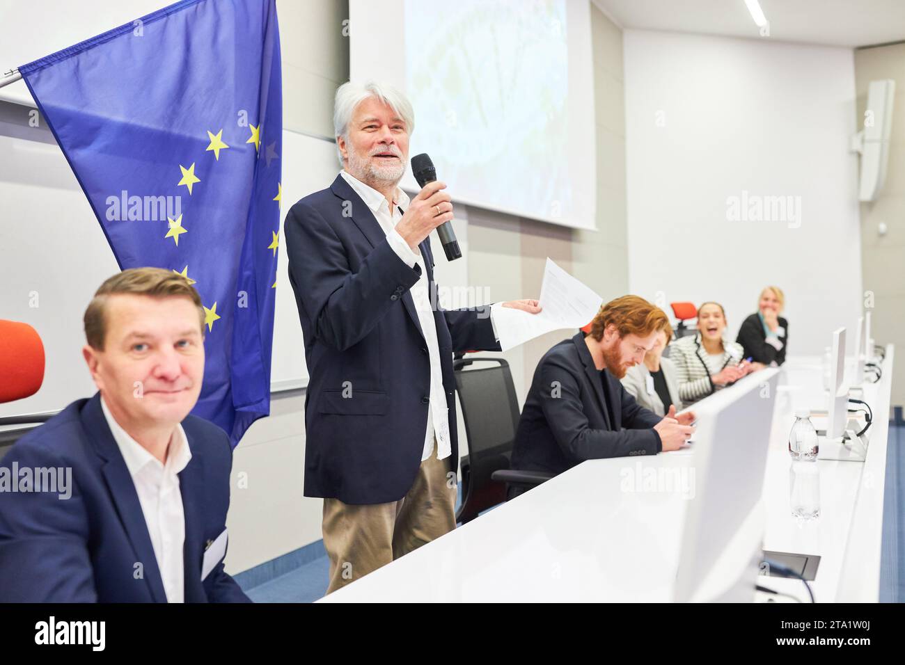 Speaker explaining while standing by professionals on stage at ...