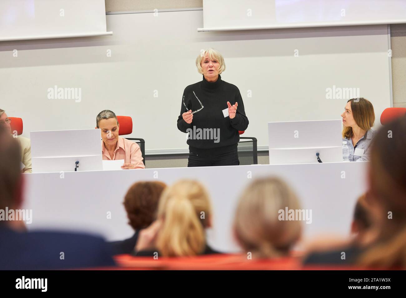Female speaker giving speech from stage during business conference in ...