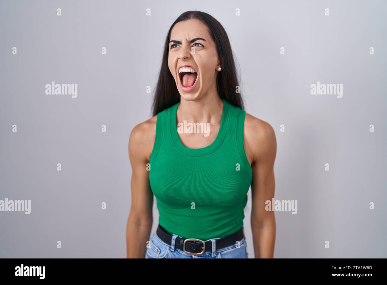 Young woman standing over isolated background angry and mad screaming ...