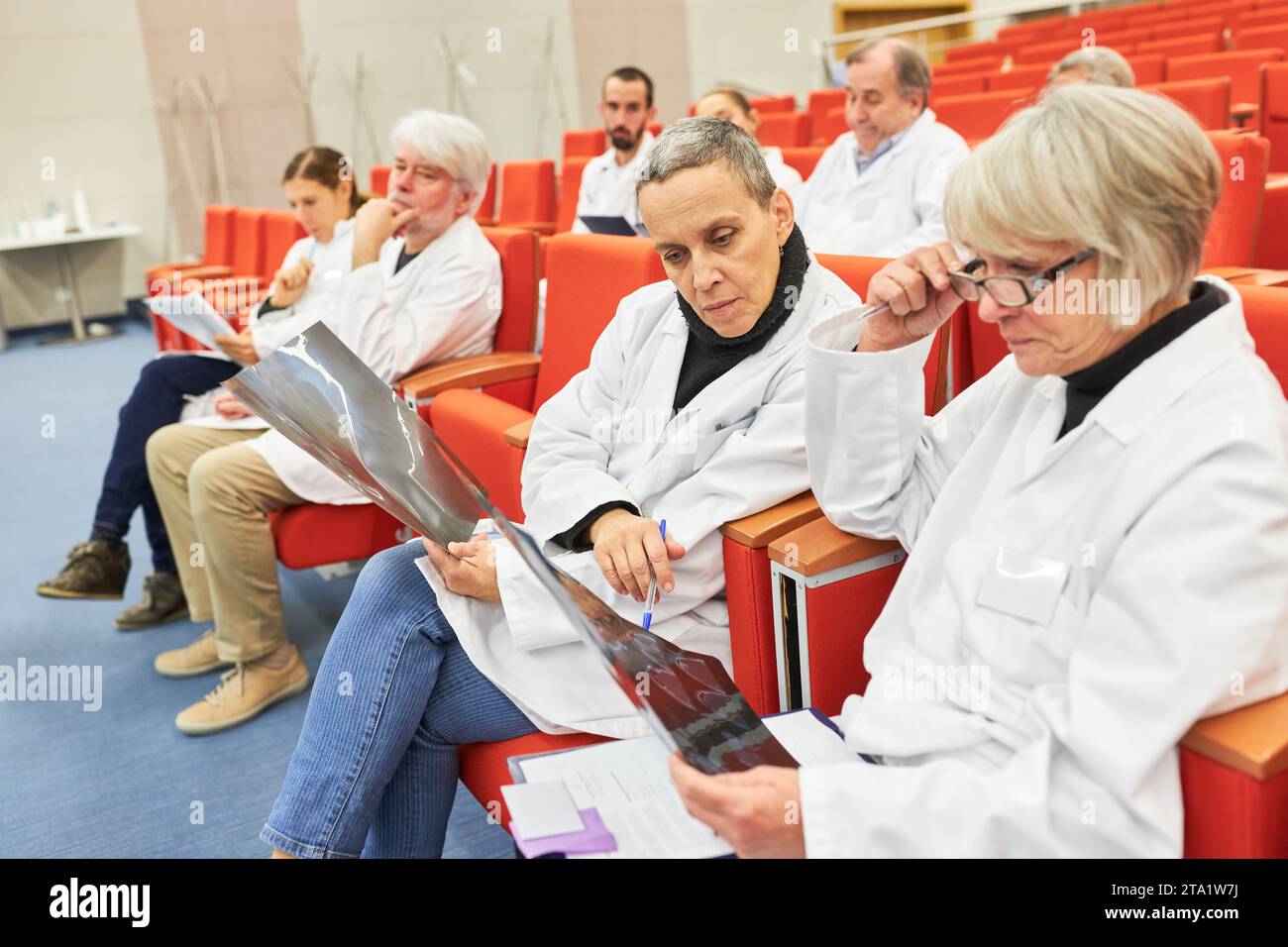 Female doctors examining x-ray while sitting in audience during medical ...