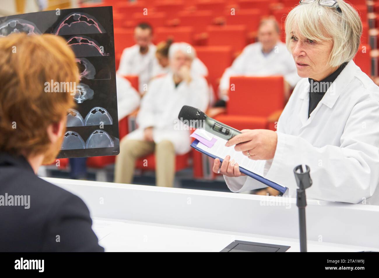 Female professional asking question to speaker while holding x-ray ...