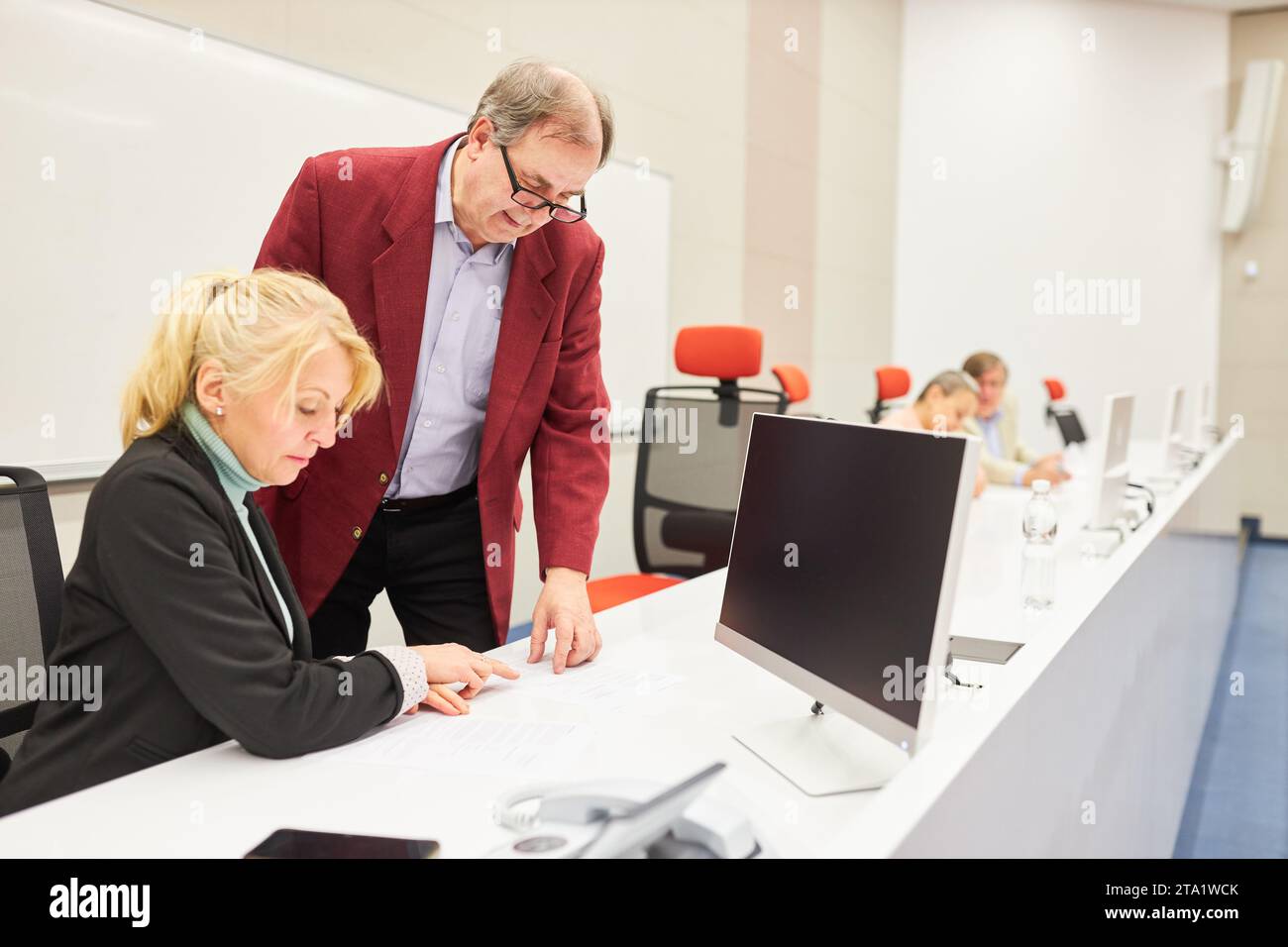 Male and female speakers discussing over document at table on stage ...