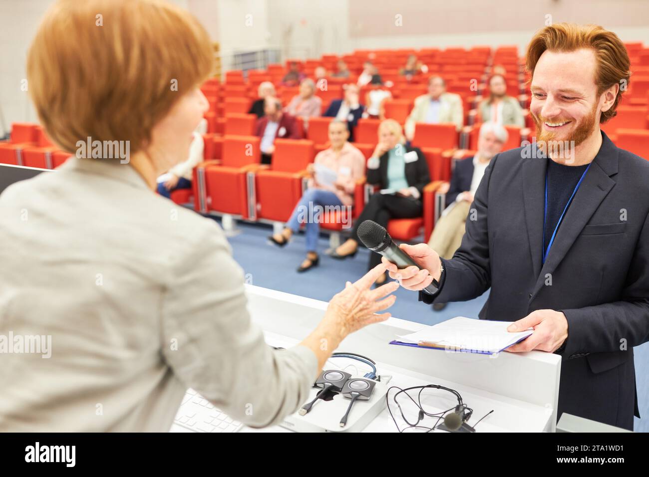 Orator giving microphone to man in audience during business session in ...