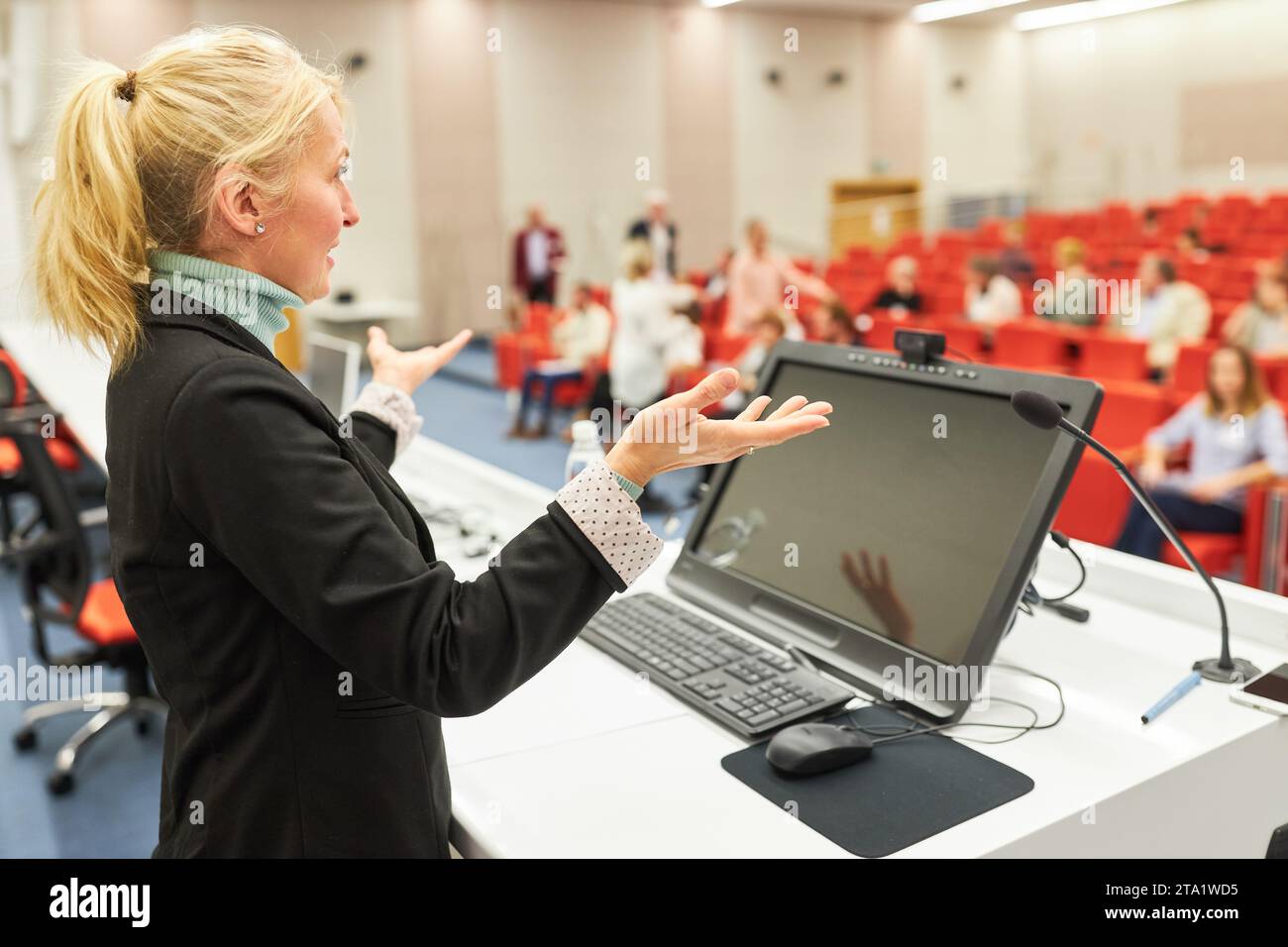 Female speaker on panel at business conference gesturing while ...