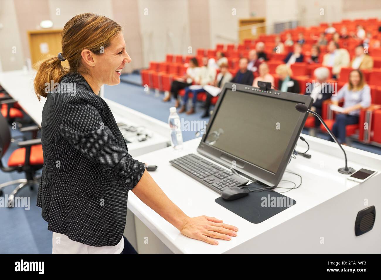 Happy female orator giving speech at podium during business session in ...