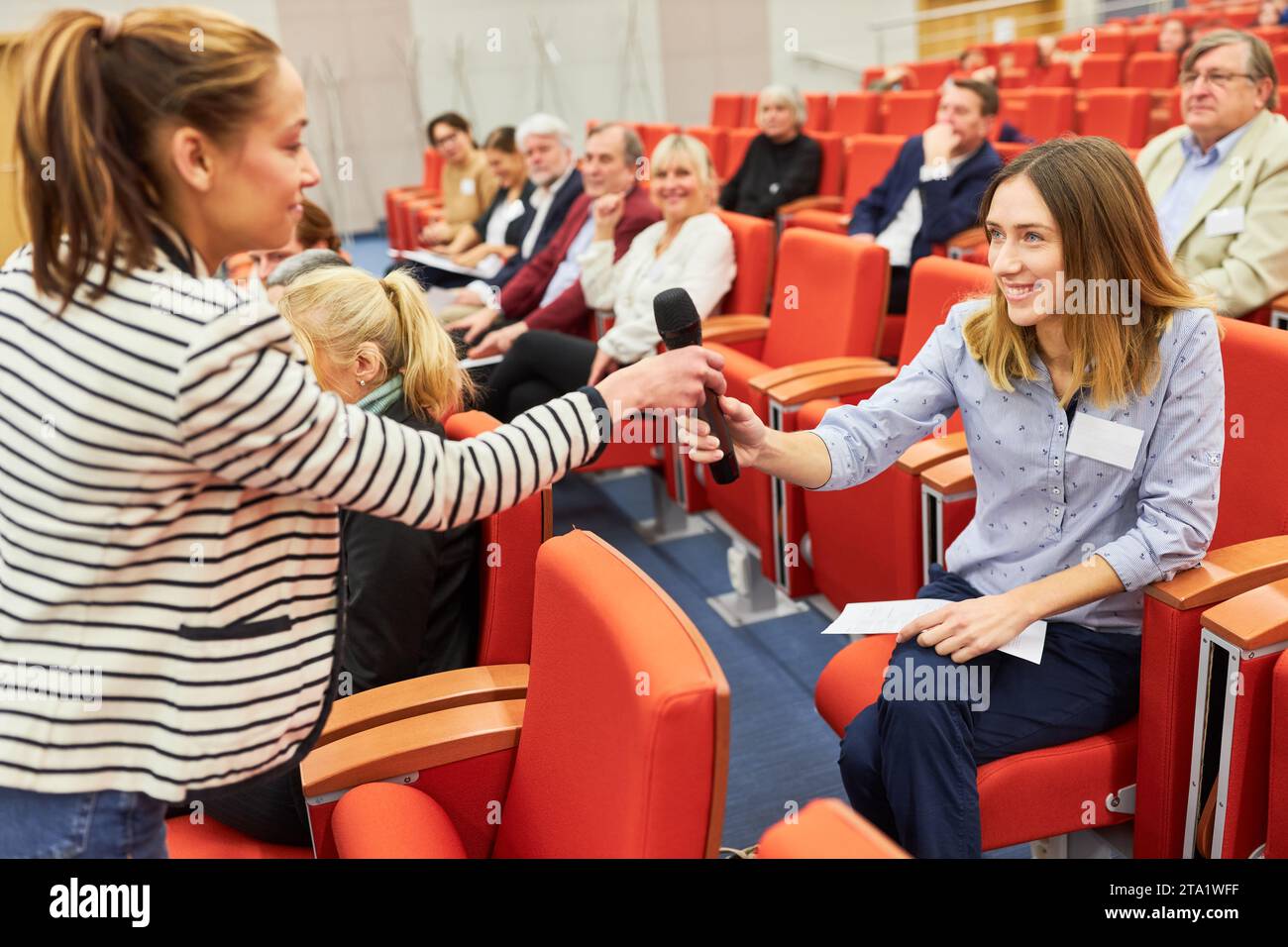 Female speaker giving microphone to businesswoman during business event ...