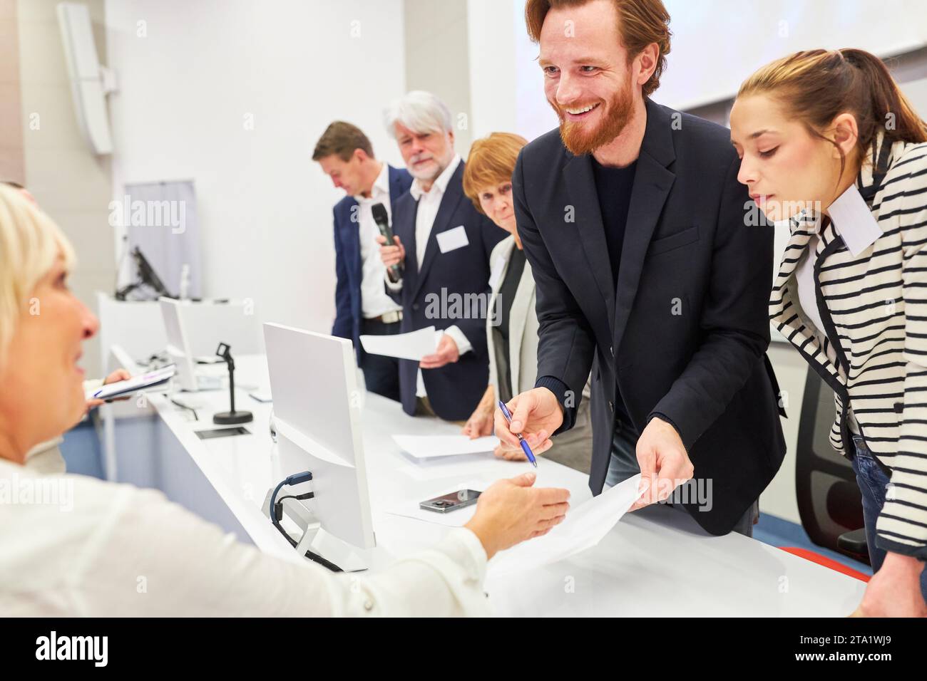 Smiling speaker explaining audience over document at panel during event ...