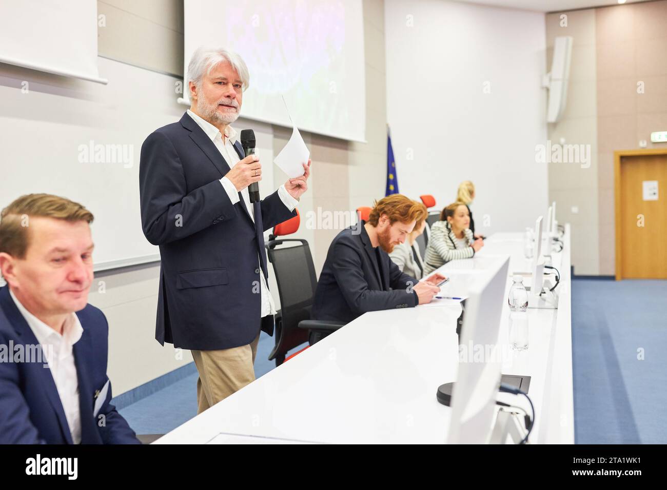 Speaker explaining while standing by professionals on stage in ...