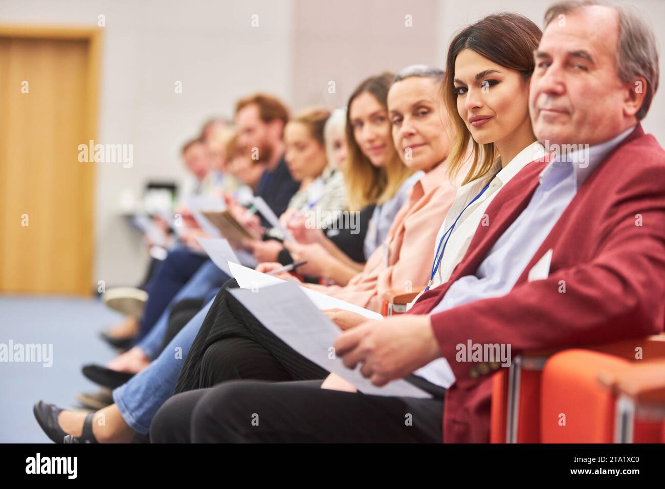 Male and female professionals sitting in audience at business ...