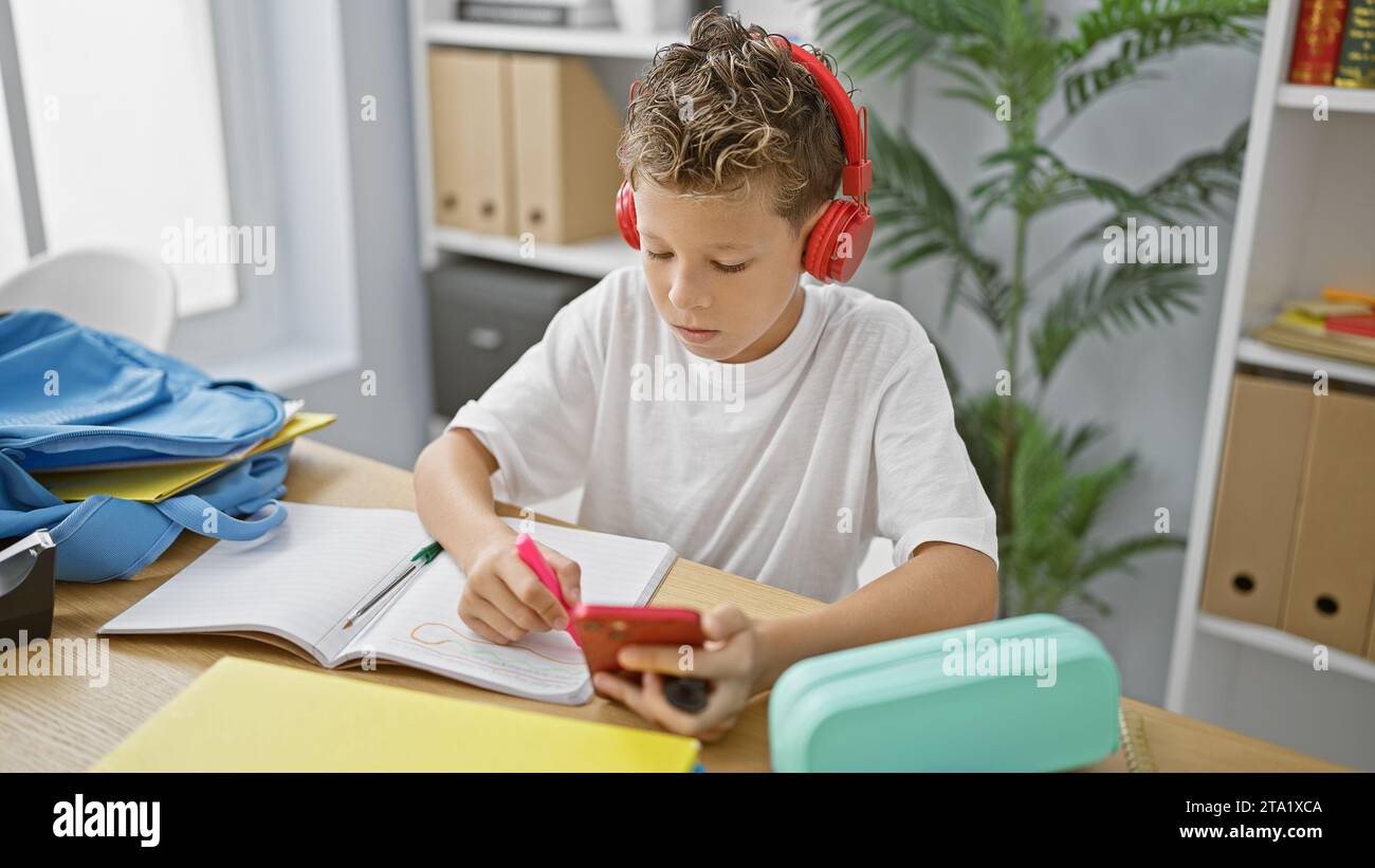 Adorable blond boy student, engrossed in listening to music on his ...