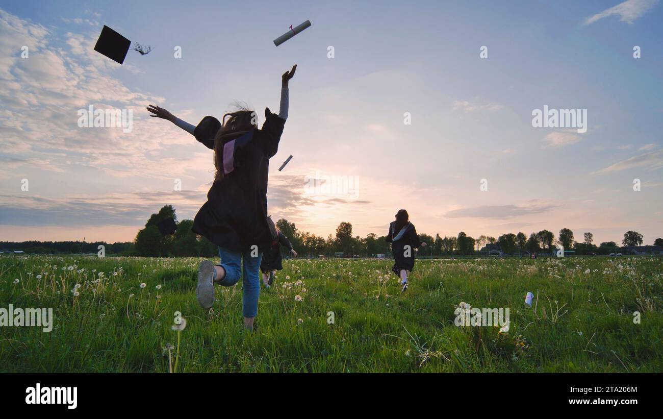Graduation girl running in the background of the sunset and throwing ...