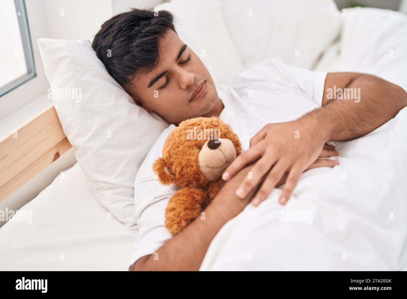 Young Hispanic Man Hugging Teddy Bear Lying On Bed Sleeping At Bedroom