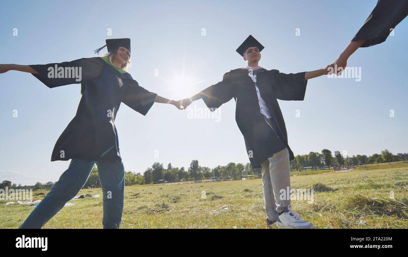 College graduates holding hands run in a round dance Stock Photo - Alamy