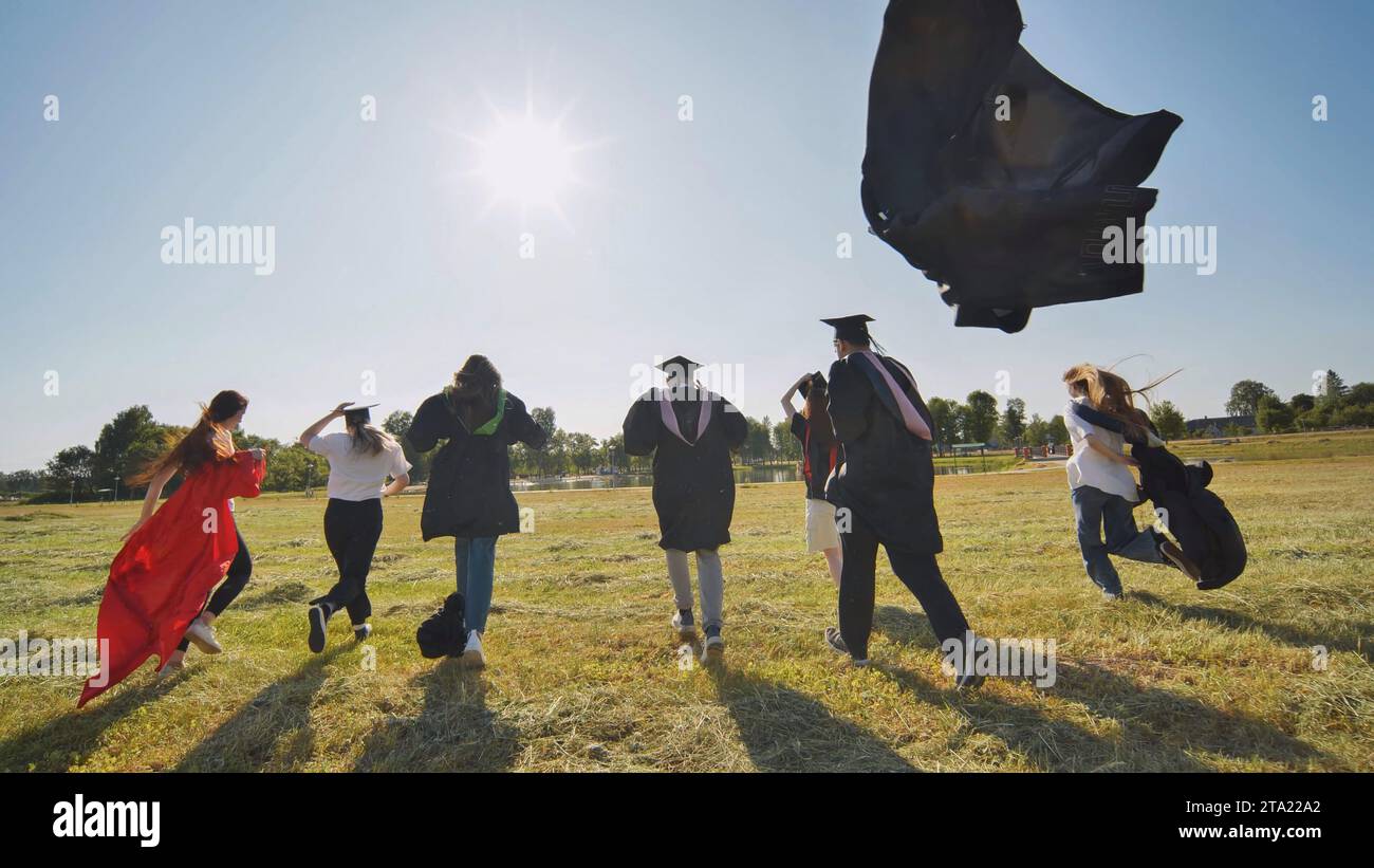 Happy graduates run in and take off their robes. The concept of ...