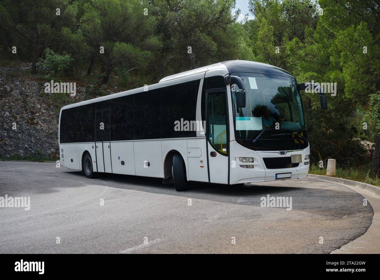 White tourist bus going around tight hairpin turn in a mountain road ...