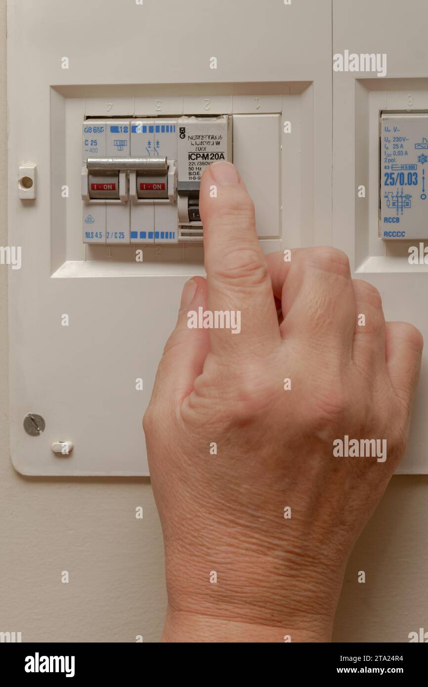 Woman pushing lever on fuse box to save energy Stock Photo - Alamy