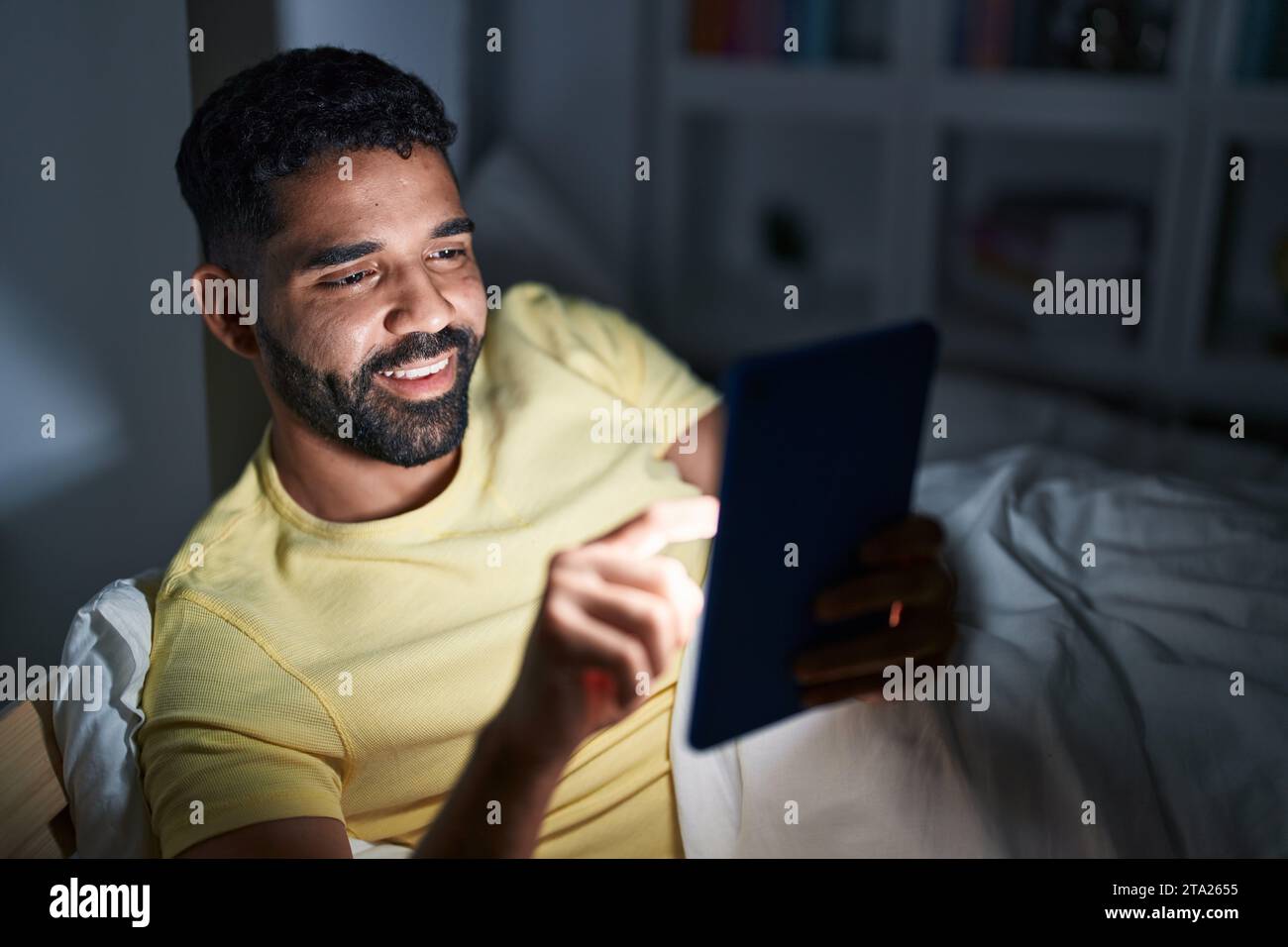 Young arab man using touchpad lying on bed at bedroom Stock Photo - Alamy