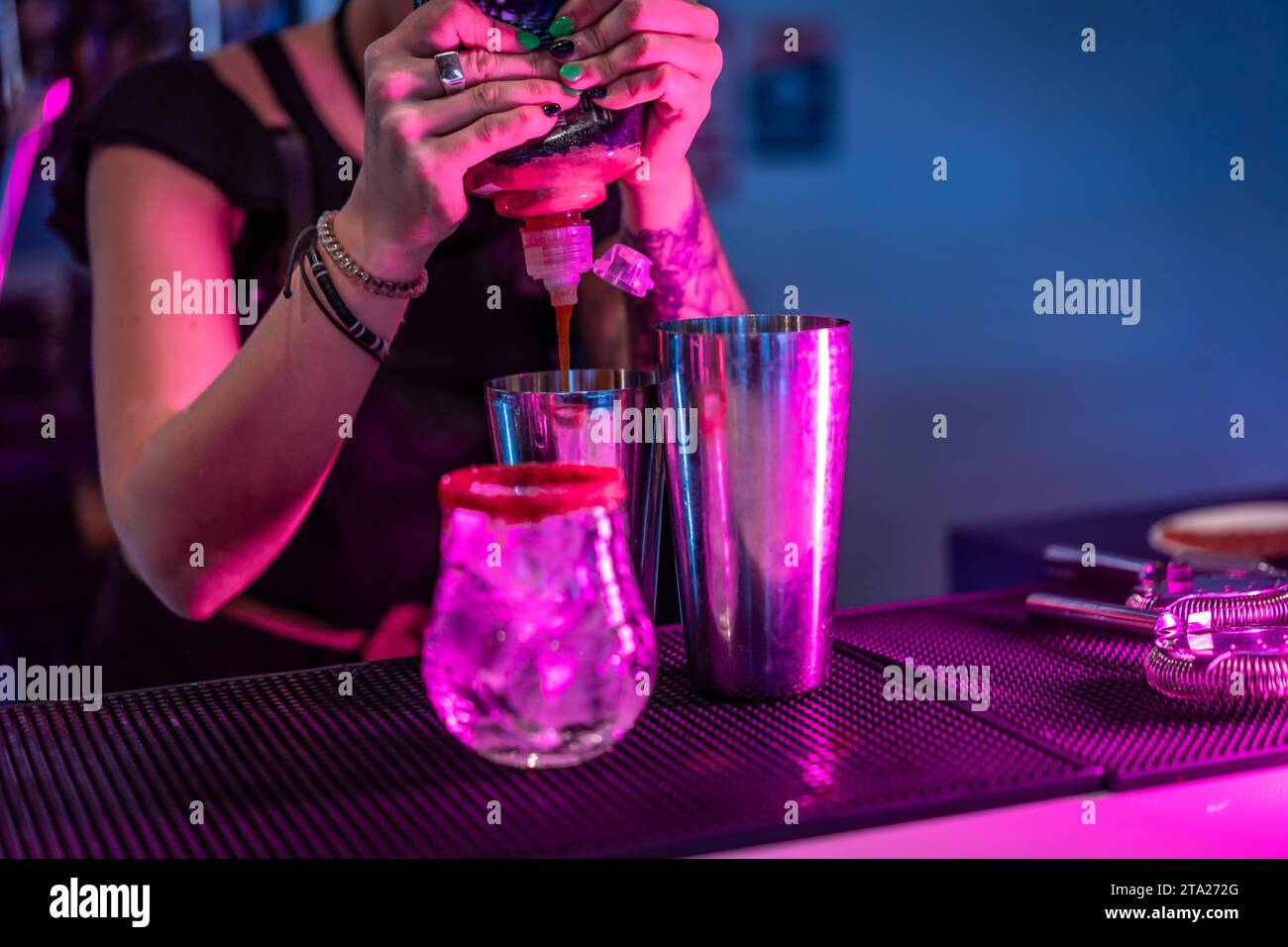 Bartender mixing ingredients in a cocktail mixer in the counter of a ...