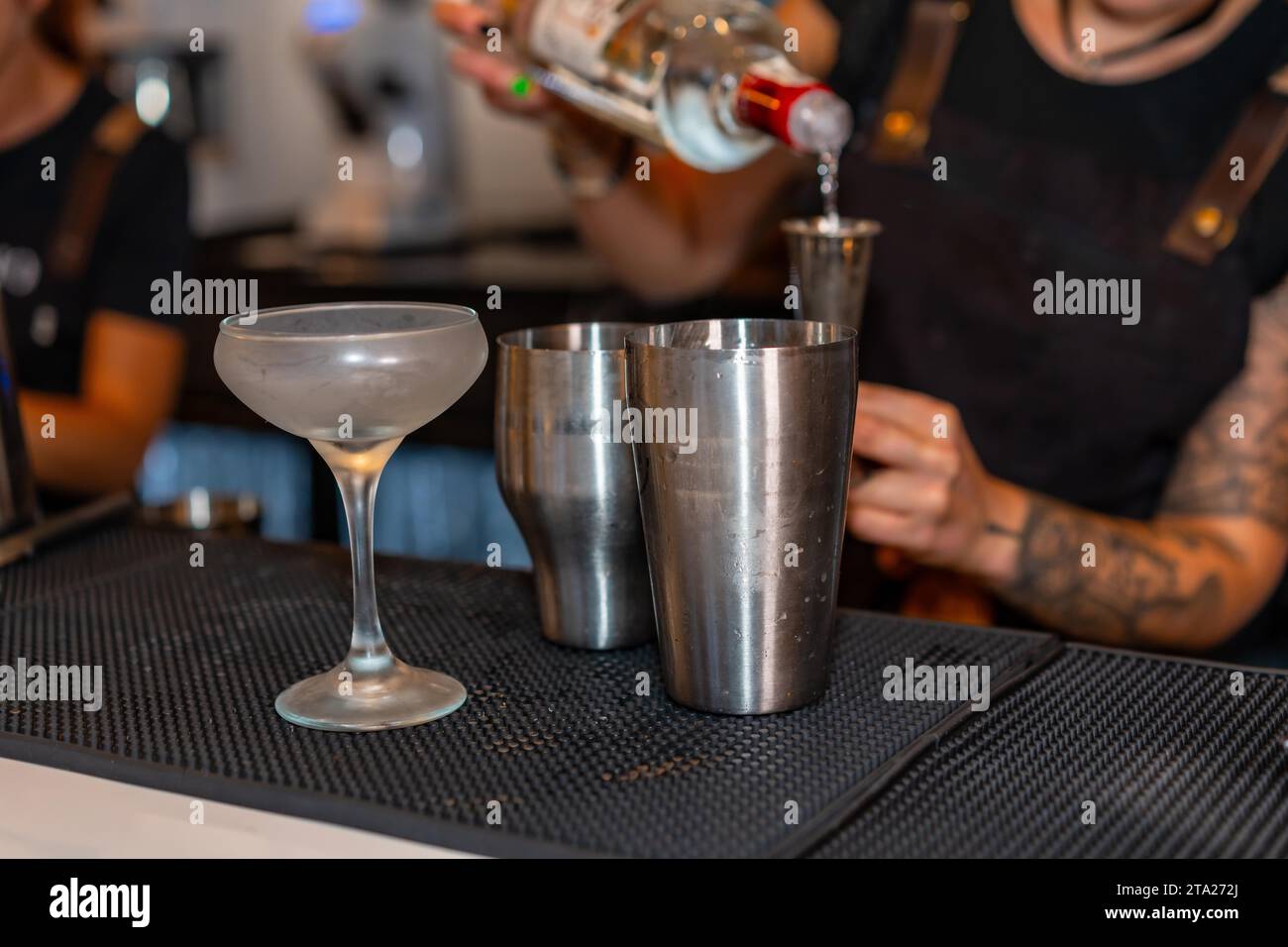 Bartender using a measuring tool to prepare a cocktail in the counter ...