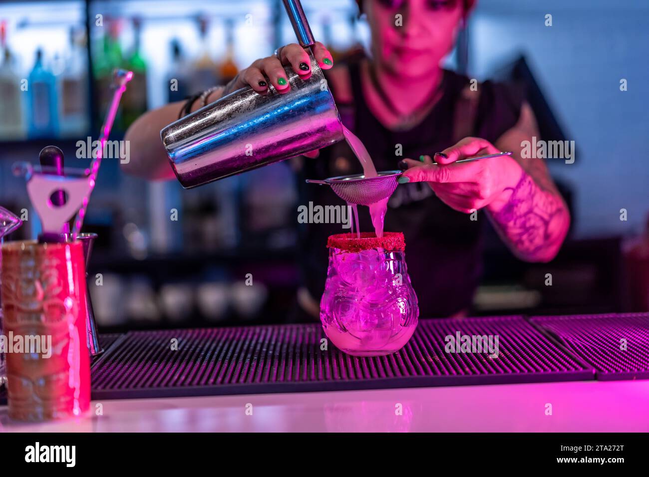 Shaker strains the ingredients into a cocktail glass in the counter of ...