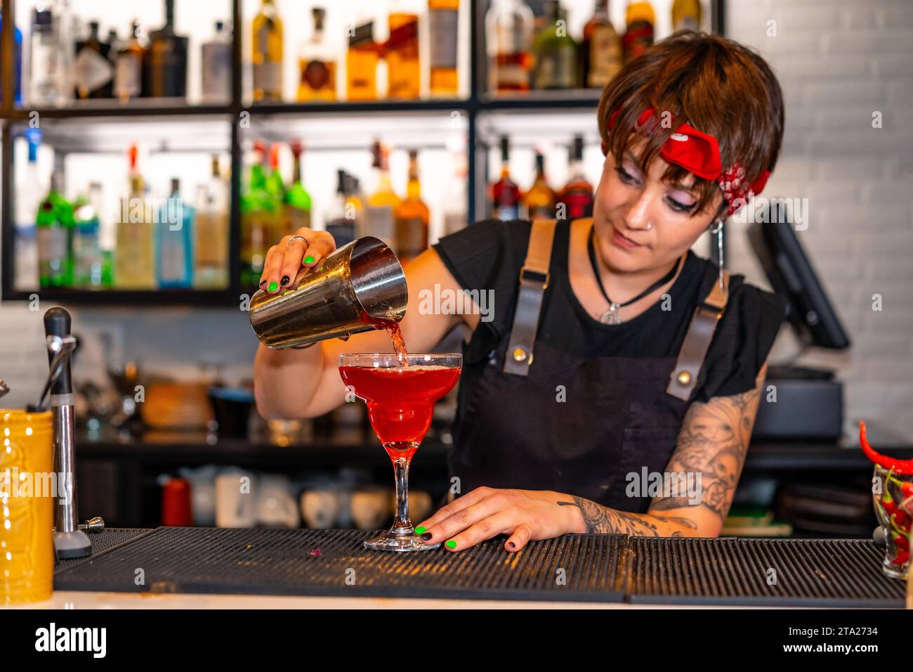 Professional young bartender preparing a red cocktail standing in the ...
