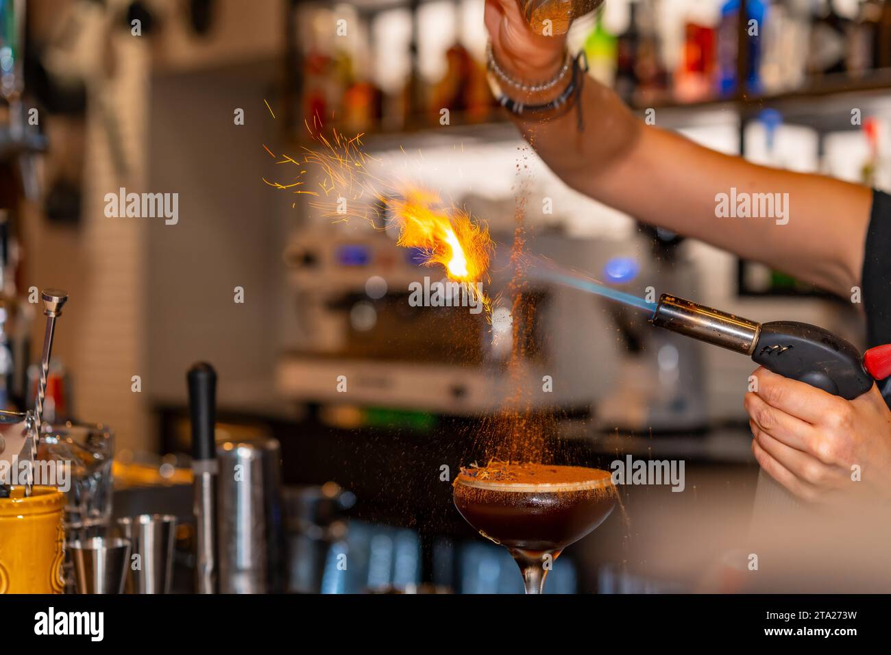 Close-up photo of an unrecognizable bartender burning the topping of a ...