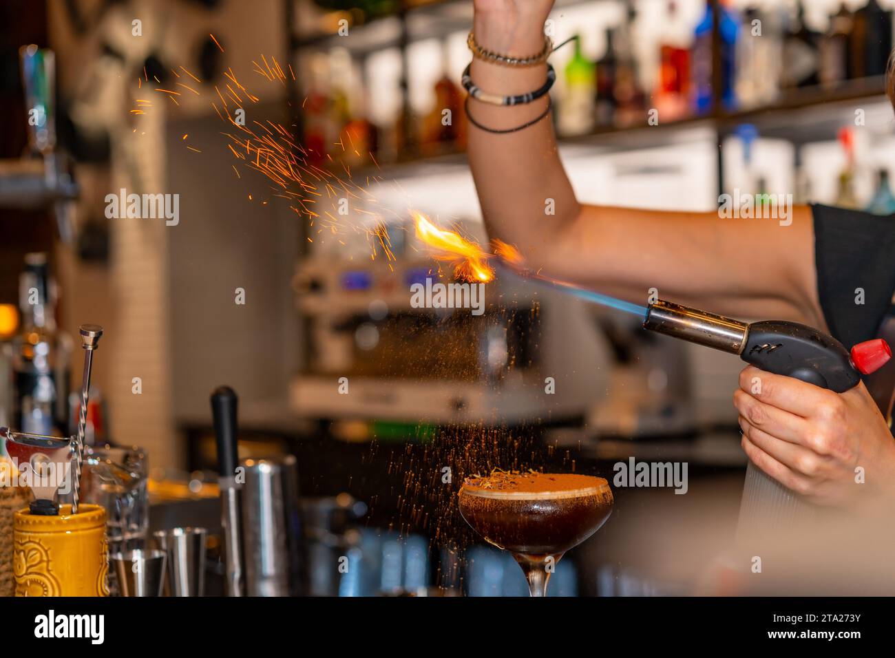 Close-up of the hands of a bartender burning the toppings of coffee ...