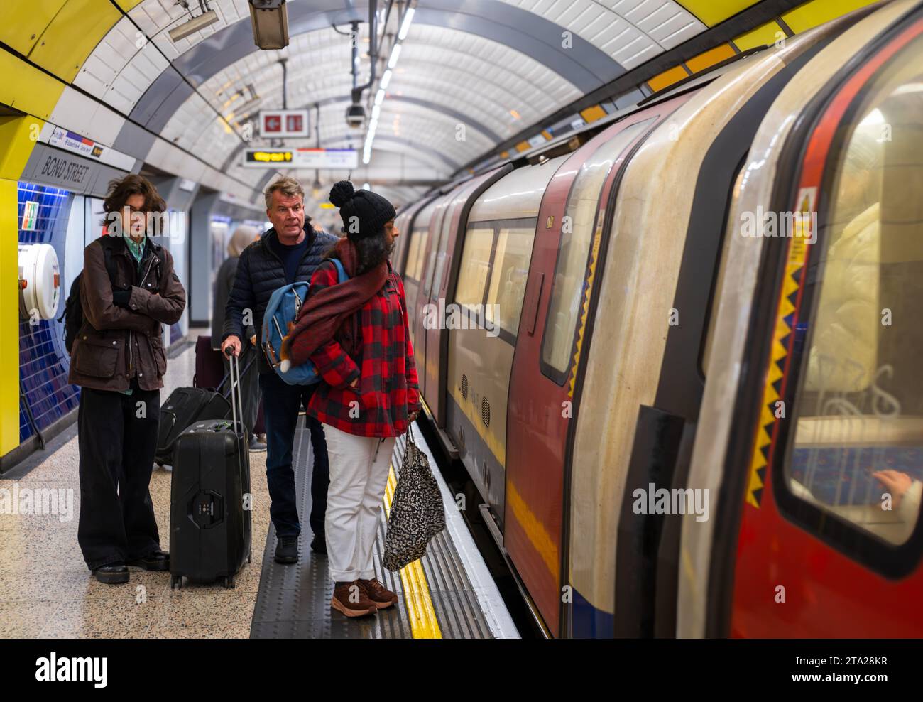 Passengers wait to board an arriving London Underground, or Tube, train at Bond Street station ...