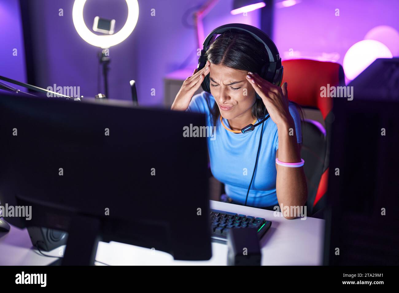 Brunette young woman playing video games suffering from headache ...