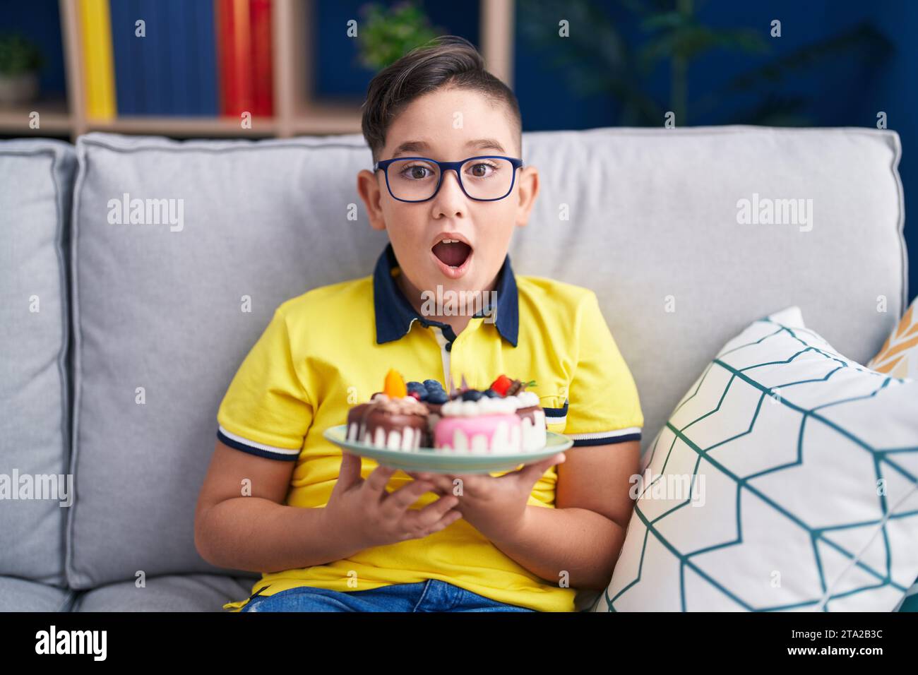 Young hispanic kid holding cake sweets celebrating crazy and amazed for ...