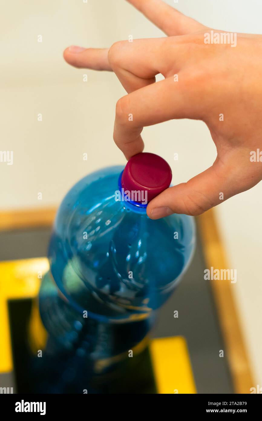 Selective focus close up hand throwing an empty plastic bottle in the recycling garbage trash or ...