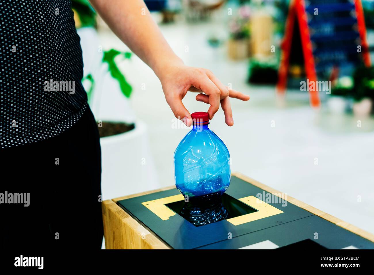 Selective focus close up hand throwing an empty plastic bottle in the recycling garbage trash or ...