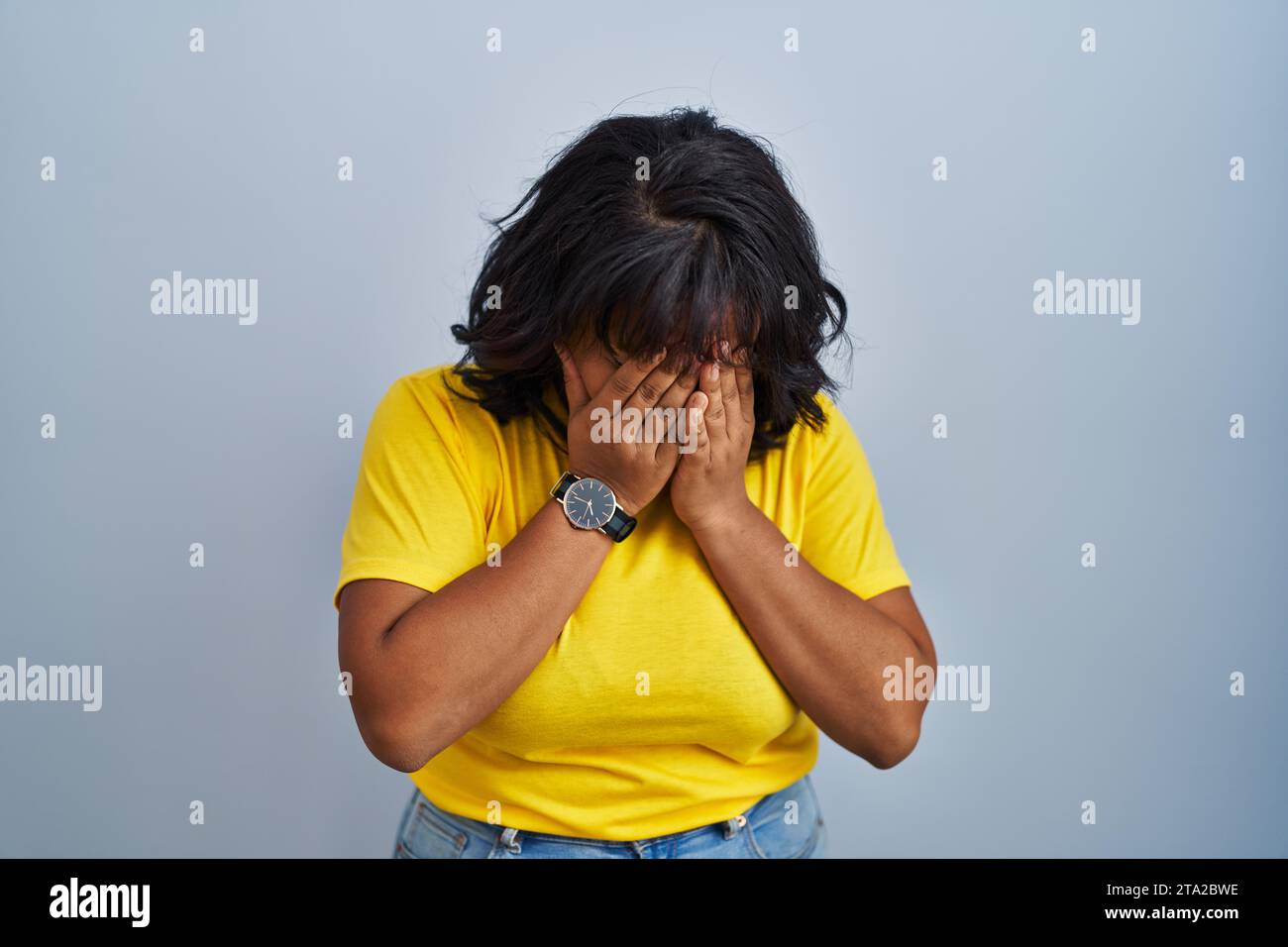 Hispanic woman standing over blue background with sad expression ...