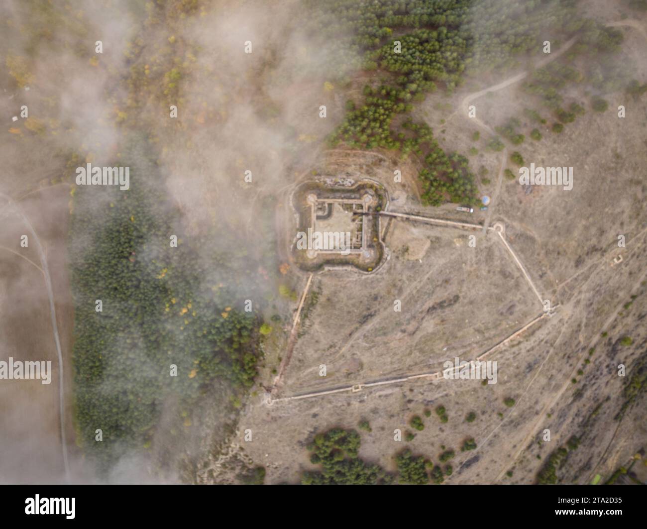 Aerial overhead view of the Llívia castle between fog and clouds ...
