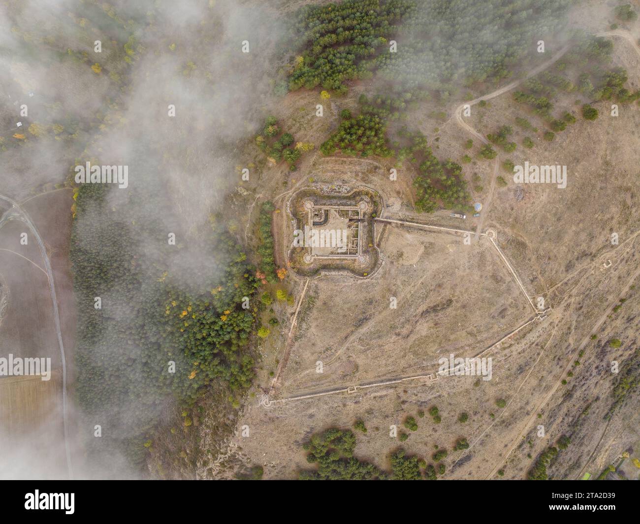Aerial overhead view of the Llívia castle between fog and clouds ...
