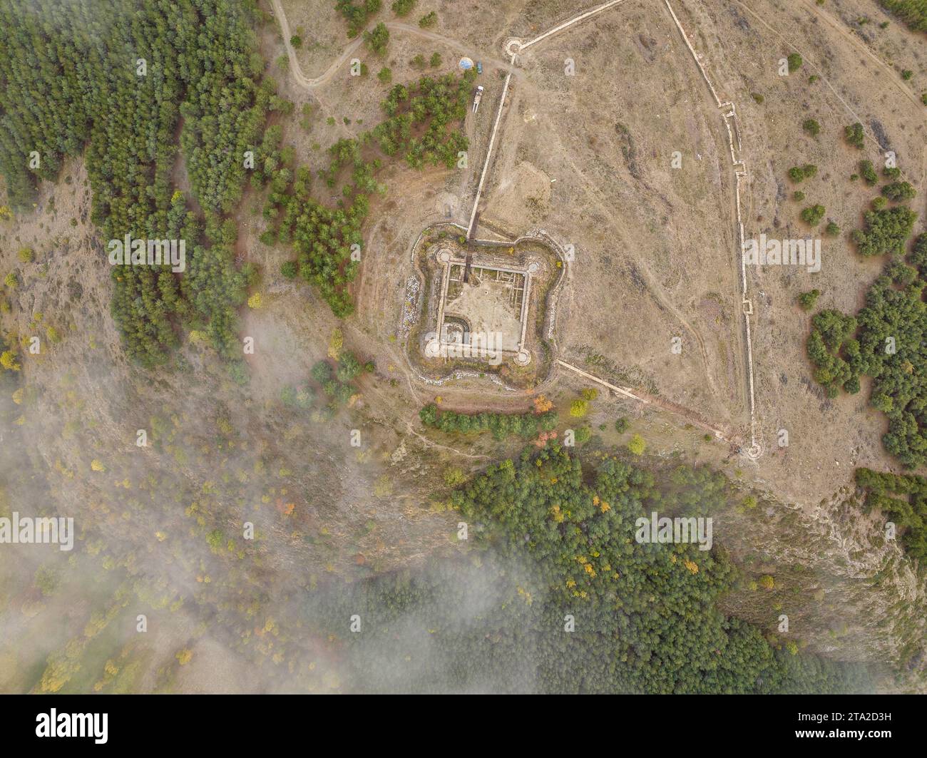 Aerial overhead view of the Llívia castle between fog and clouds ...