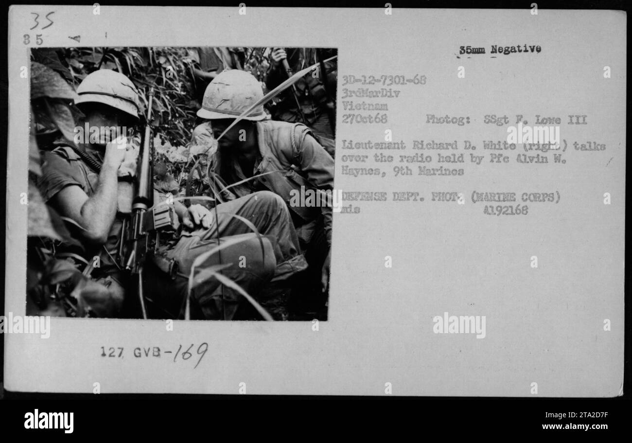 Lieutenant Richard D. White (right) communicates over a radio held by ...