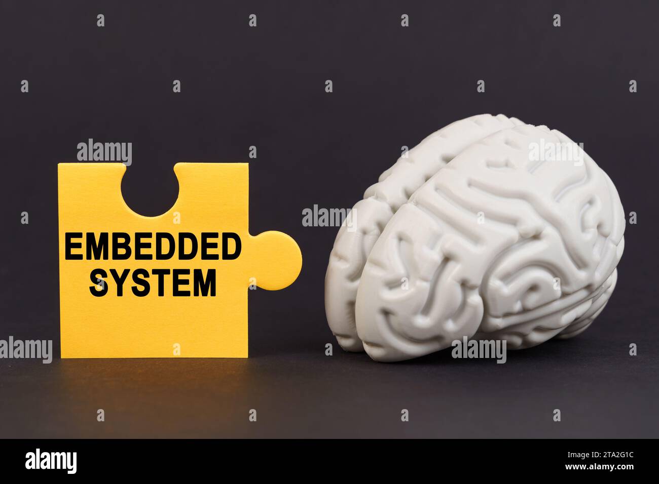 On a black surface there is a brain and a yellow puzzle with the ...