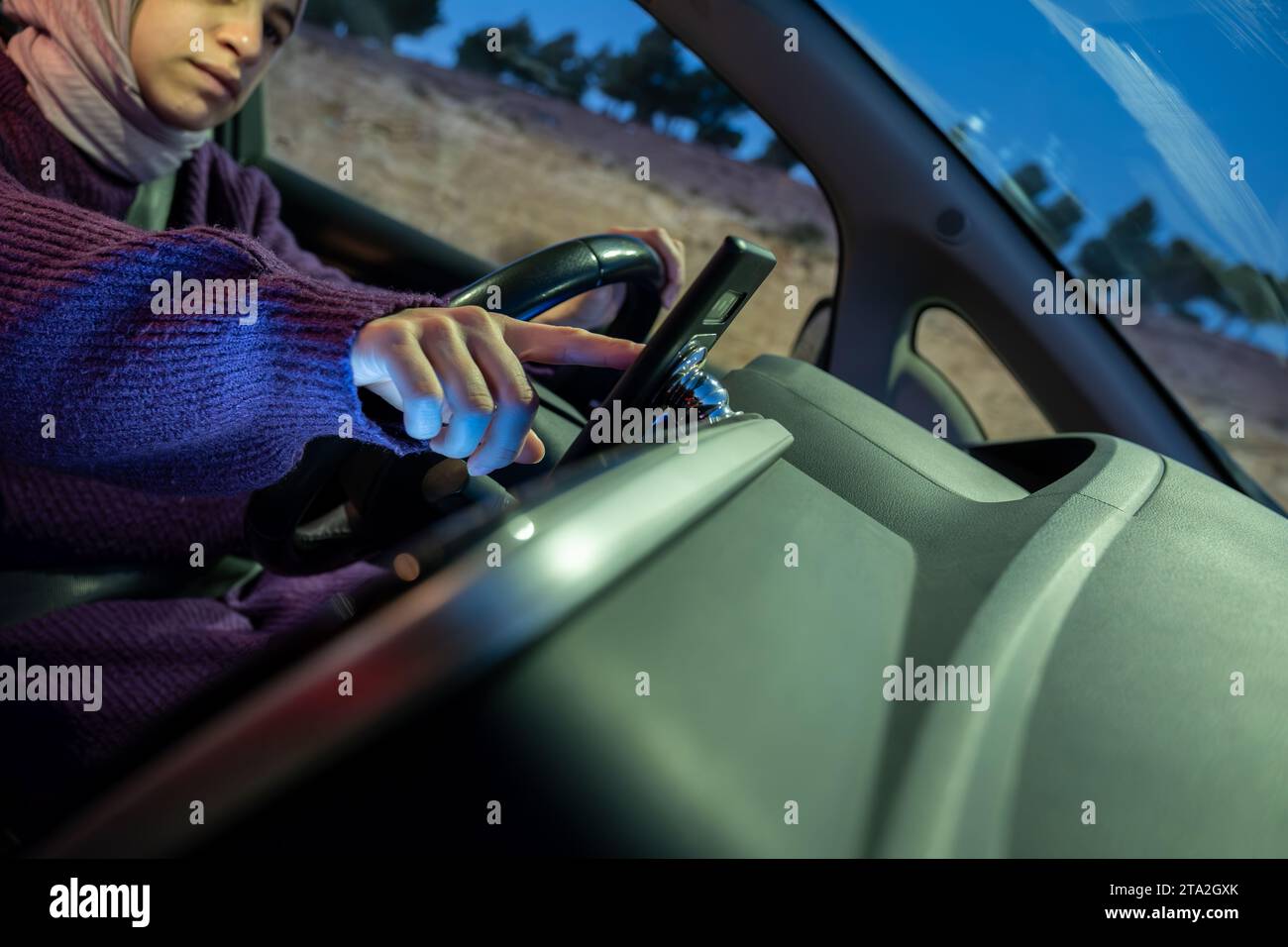 Pregnant arabic muslim woman driving car at night wearing winter ...