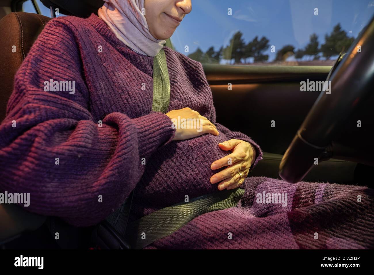 Pregnant arabic muslim woman driving car at night wearing winter ...