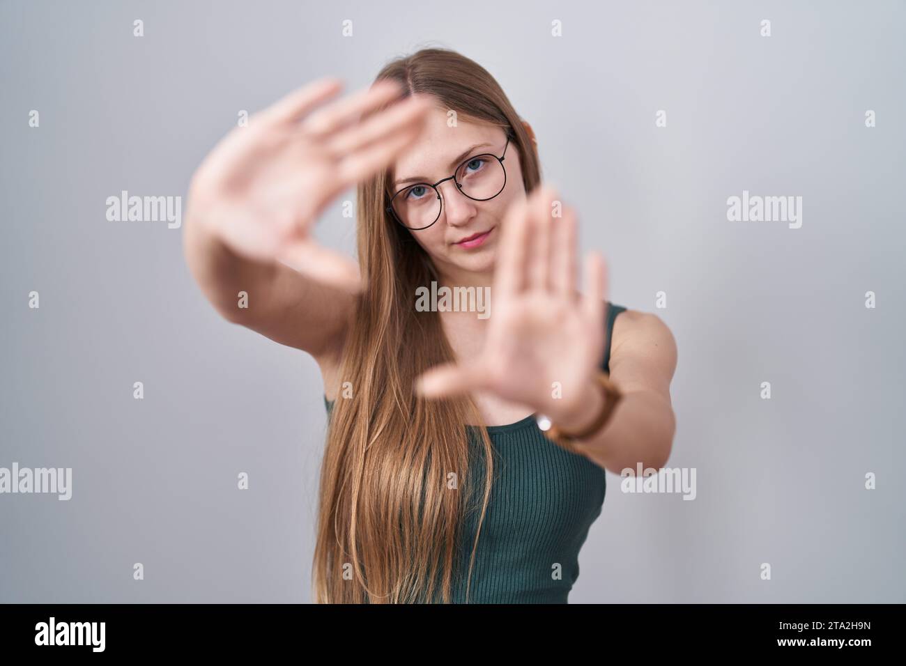 Young caucasian woman standing over white background doing frame using ...