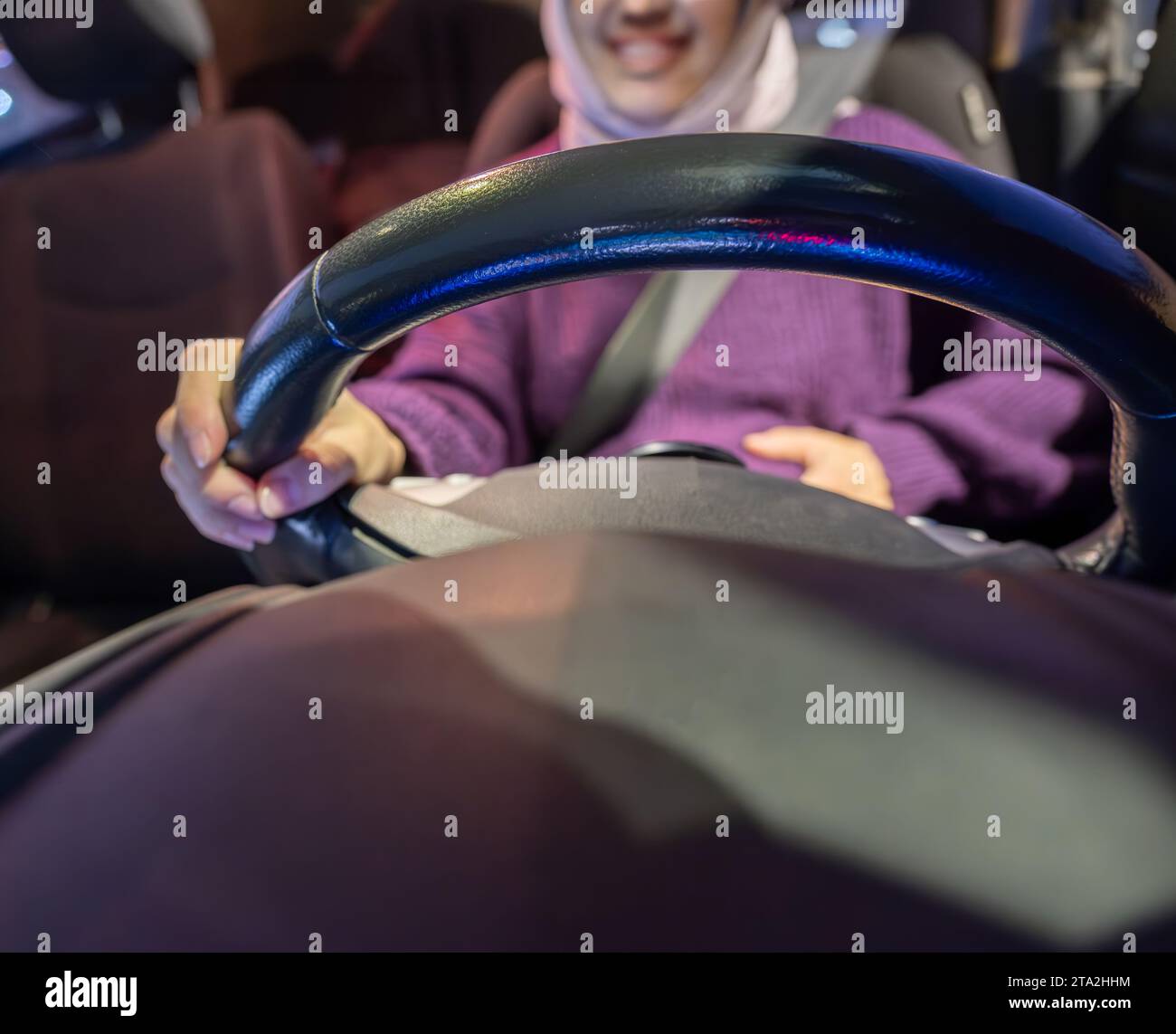 Pregnant arabic muslim woman driving car at night wearing winter ...