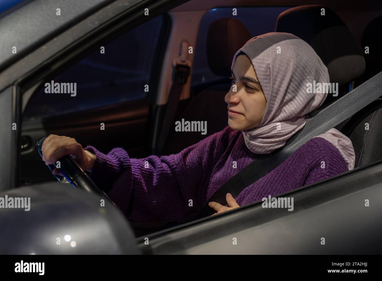 Pregnant arabic muslim woman driving car at night wearing winter ...