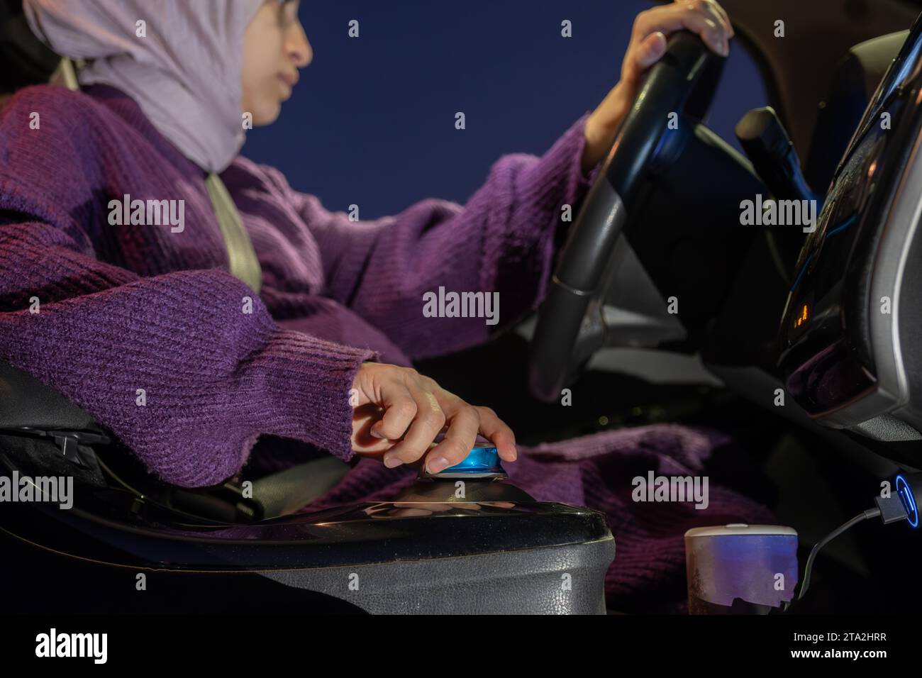 Pregnant arabic muslim woman driving car at night wearing winter ...