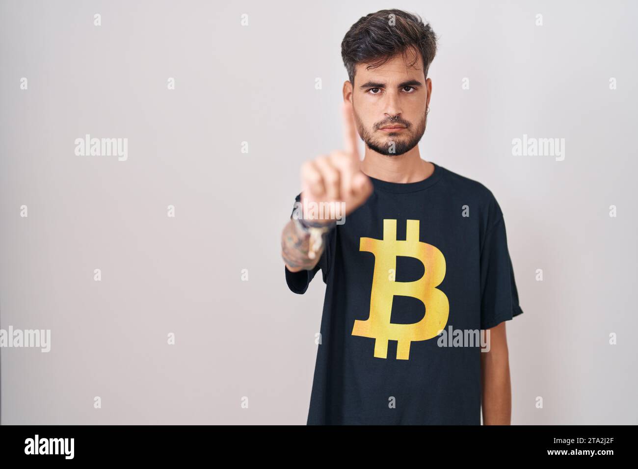 Young hispanic man with tattoos wearing bitcoin t shirt pointing with ...