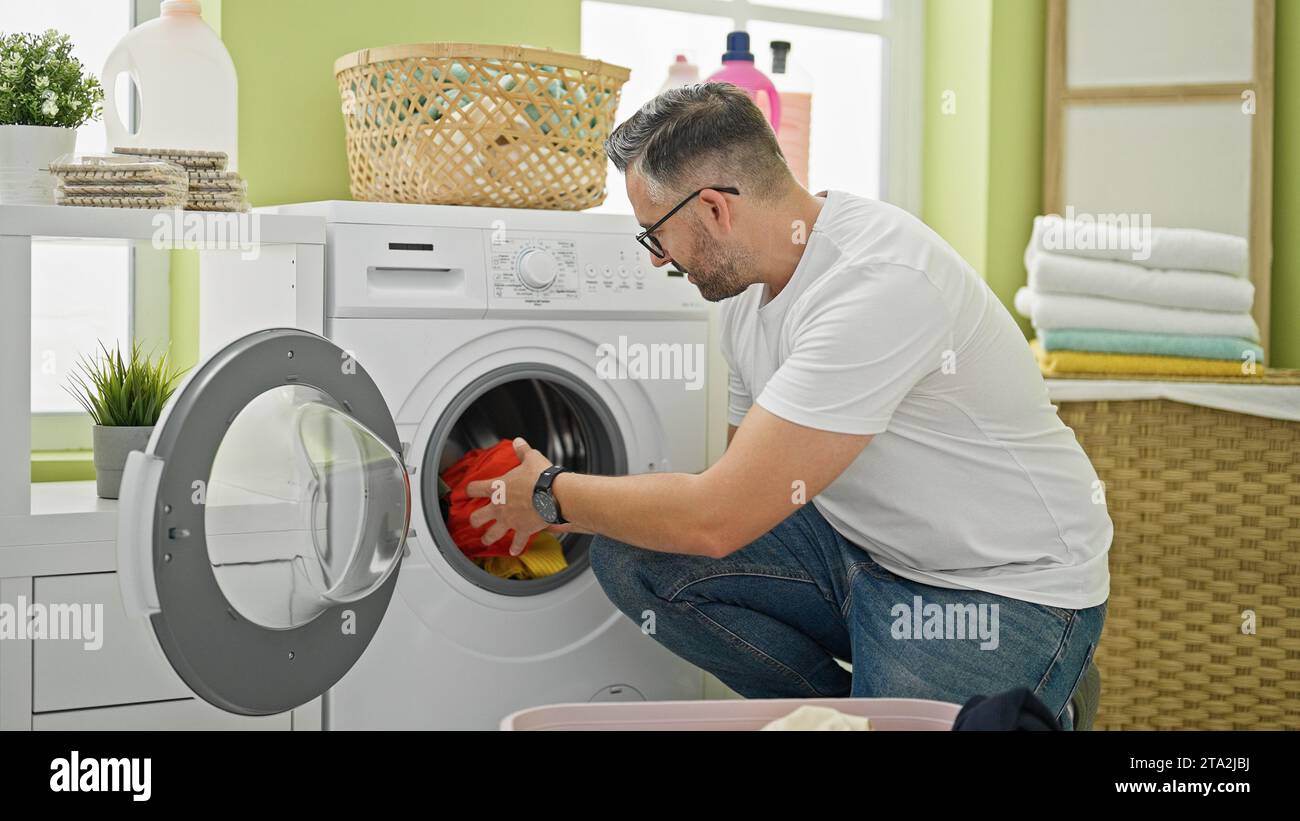 Grey-haired man washing clothes at laundry room Stock Photo - Alamy