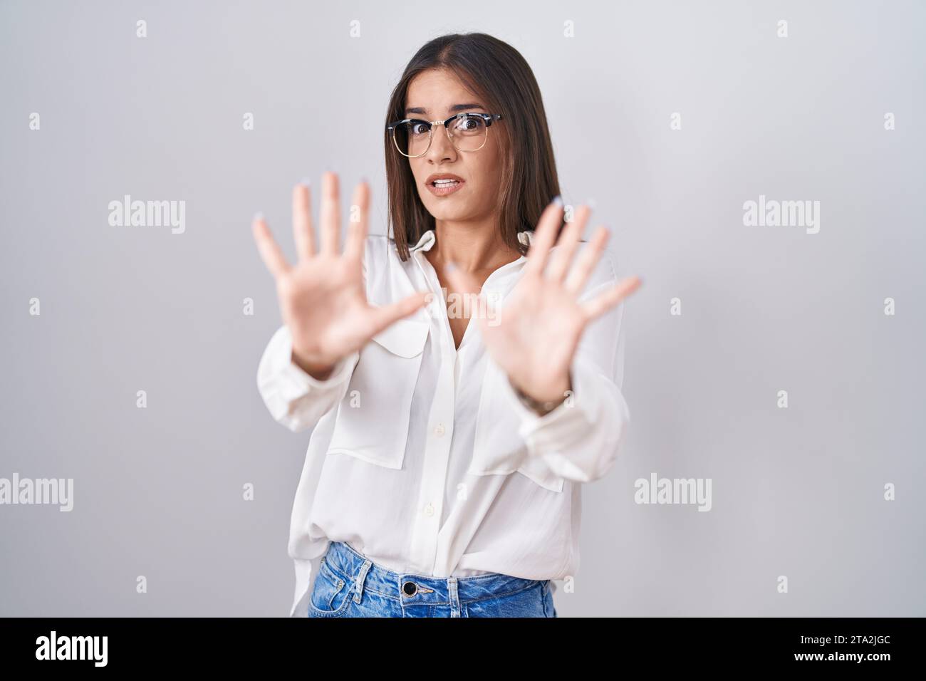 Young brunette woman wearing glasses afraid and terrified with fear ...